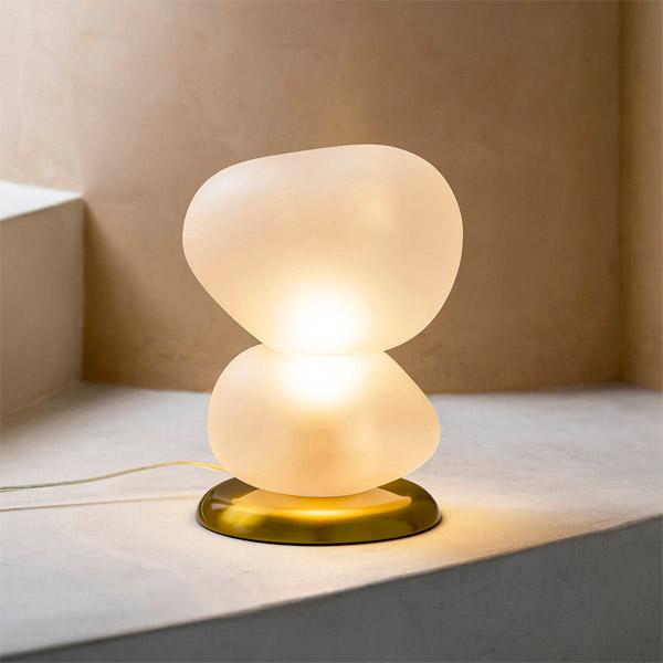 不規則で有機的なシルエットがアブストラクトアートを思わせるインテリア性の高いウニネンテーブルライト。アシンメトリーな2つのフォルムを半透明のフロストガラスで表現しています。ふわりとした明かりがかすかな輪郭を浮かび上がらせ、癒やしのひとときを...