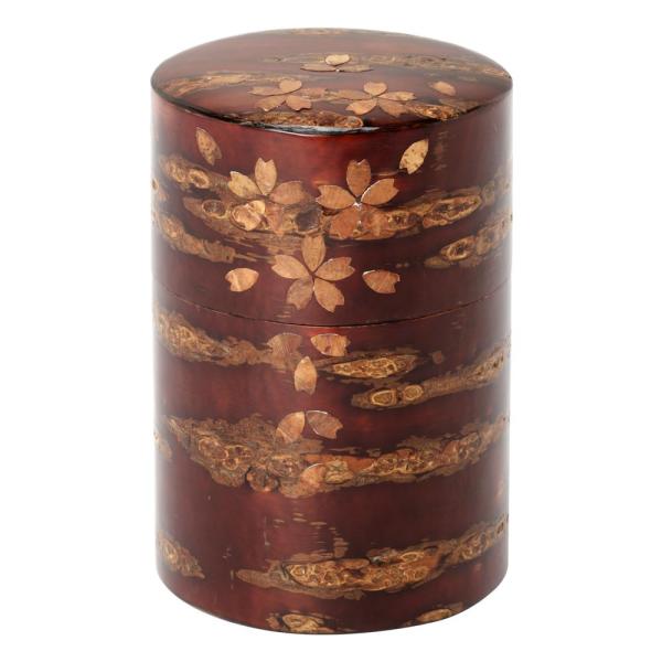 スタンダードな茶筒「総皮茶筒　無地皮」に、桜の花びらが散る情景を桜皮で表現した茶筒。日々、手沢によって光沢が増し、使い込むほどに落ち着いた色味に変化していきます。