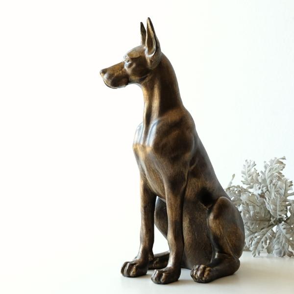 凛とした立ち姿と鋭くも知的な表情の樹脂製のドーベルマンの置物はドーベルマン特有の美しく引き締まった筋肉美や力強さを細部まで再現しています玄関のウェルカムオブジェとして書斎やリビングのアクセントとして空間に品格をもたらしそうなアイテムです商品...