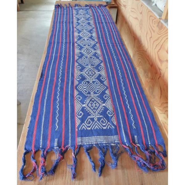 インドネシア、スンバ島で作られた絣布（イカット、ikat）です。元々は男性用の腰布または肩掛け布として使われていましたが、イカットの持つデザイン性に人気がありインテリアとして親しまれています。長さ110cm前後、奥行が約37cmで、テーブル...