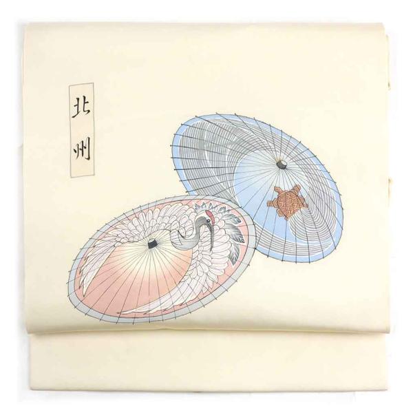 正絹の九寸名古屋帯です。生成色に鶴と亀が描かれた傘の柄で紬や小紋などカジュアル用途の着物に合わせてお使いいただけます。「北州」と書かれており柄に何かの物語があるのかと思いますが詳細不明です。何度か使用されているようで、傘の柄の部分の中心にご...