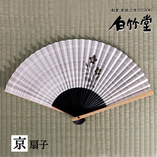 上絵職人によって1枚1枚丁寧に描かれた桔梗の花が上品な京扇子。同系色で刷毛引きを重ねることによって、よりシックな印象に。親骨には銘竹として貴重なごま竹を採用し、竹の斑紋、自然素材そのままの風合いをお愉しみいただけます。【品名】親ゴマ桔梗 扇...