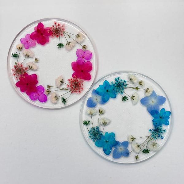 【発売日：2025年09月16日】・透明なレジンに、可憐な押し花をひとつひとつ丁寧に閉じ込めたコースターです。　まるで小さな花のリースのようにテーブルを彩ります。グラスを置くだけで、日常のひとときが少し特別に。　ご自宅用にはもちろん、ご友人...