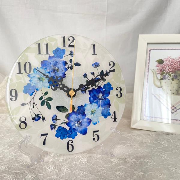 【発売日：2021年05月31日】・押し花をUVレジンでコーティングしたハンドメイドの花時計です。掛け時計・置時計どちらでもご利用いただけます！・グリーンリーフプリントの円形アクリル板に数字が印刷してありますので、表面はフラットになっていま...