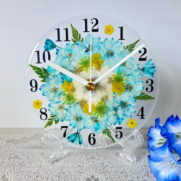 【発売日：2021年05月31日】・押し花をUVレジンでコーティングしたハンドメイドの花時計です。掛け時計・置時計どちらでもご利用いただけます！・円形のアクリル板に数字が印刷してありますので、表面はフラットになっています。ハンドメイドのため...