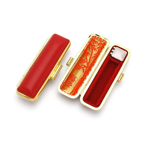 個人印（実印・銀行印・認め印など）を収納する、金色の枠が高級感ある印鑑ケースです。様々なシーンに対応できる、スタンダードな印鑑ケースです。外張りは艶のある赤の合成皮革を使用しています。フタ裏には「朱竹」柄の装飾生地を使用しております。朱肉が...