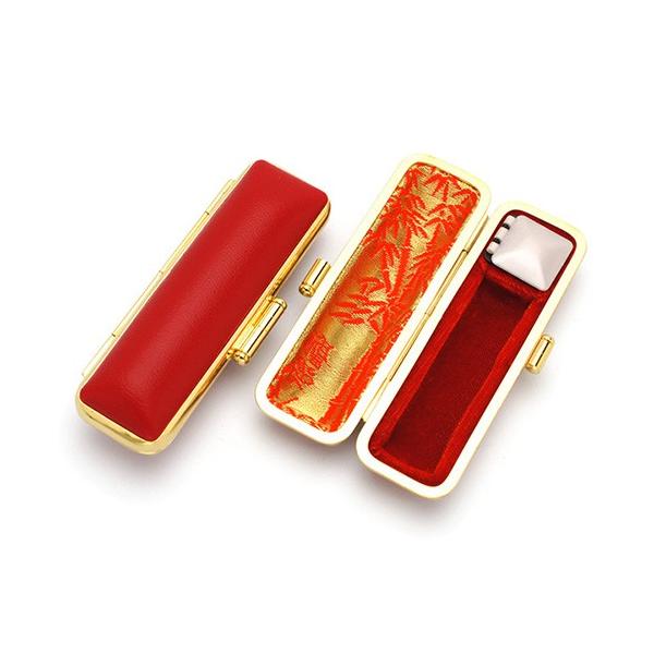 個人印（実印・銀行印・認め印など）を収納する、金色の枠が高級感ある印鑑ケースです。様々なシーンに対応できる、スタンダードな印鑑ケースです。外張りは艶のある赤の合成皮革を使用しています。フタ裏には「朱竹」柄の装飾生地を使用しております。朱肉が...