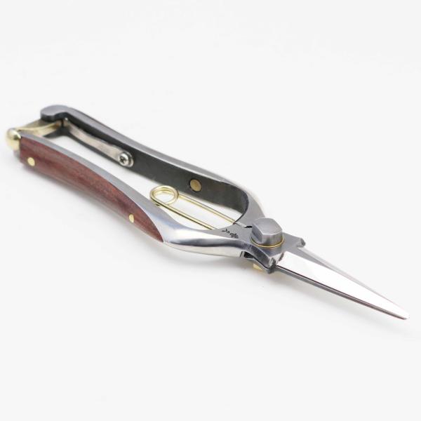 手造り（鍛造）の剪定芽切鋏です。特徴のある刃は剃刀のように鋭く植物の切り込み、剪定に最適です。全行程を手作業で加工しており持ち手には天然木「ブビンガ」の木を張り握り心地が特別な良さを感じさせます。　品番：Ｔ‐１０８全長：２００ミリ重量：１６...