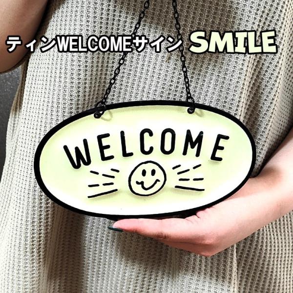 「ティンWELCOMEサイン スマイル 」優しいアイボリーカラーにスマイルが描かれたWELCOMEサインの小ぶりなブリキ看板です。エンボス加工（凹凸加工）を屈した立体的なデザインになっておりおしゃれな仕上がり。吊り下げるだけなので、お部屋を...