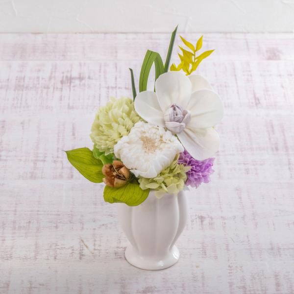 ■お届け 3日後以降でご指定可■注文締切2026/09/27　14:00まで白花を中心に、淡黄、紫の花々がやさしく調和する仏事用アレンジメント。丸みのある白い器が柔らかな印象を添え、空間に穏やかな灯りをともすような佇まいです。コンパクトなが...