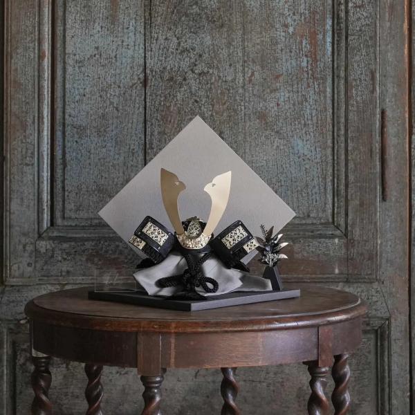 サイズ　|　横幅37×奥行33×高さ34cm黒小札・黒糸威、金物類はシャンパンゴールドの現代的な色使いの兜飾りです。鉢は、三角錐状の複数の鉄を、金星でつなぎ合わせて鉢の半円を製作した矧ぎ合わせ兜です。格安な型抜き鉢(プレス鉢)に比べ、強度を...