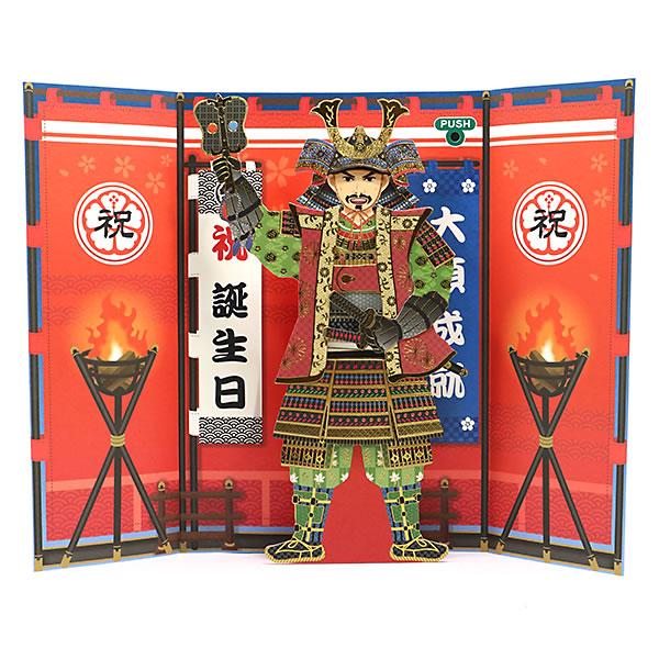 半立体で表現された戦国武将が、陣幕の前で軍配をふるう立体カードです。ボタンを押すと「ぶおぉー、ぶおぉー」とホラ貝の音が流れ、武将が「新しい一年にいざ出陣！」「大活躍の一年をお過ごしくだされ！」などのメッセージを勇ましく伝えます。武将が身につ...