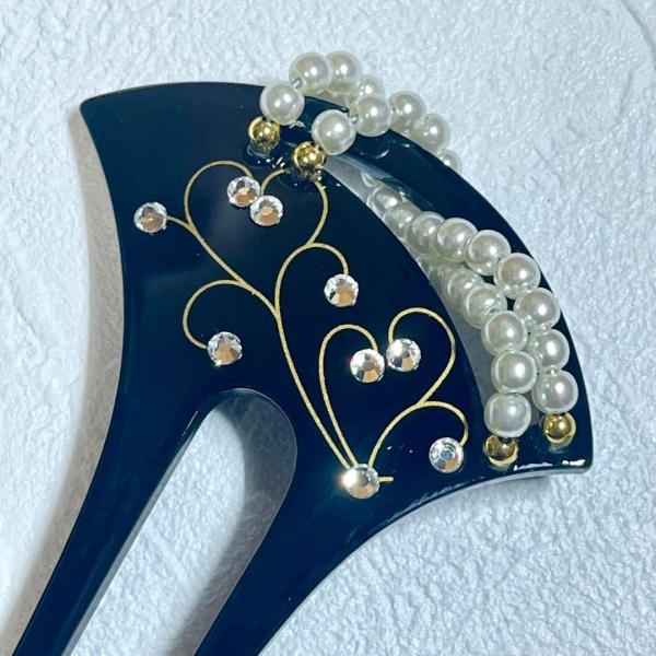 和装のまとめ髪を美しく彩る、上品なパールとラインストーンをあしらったバチ型かんざしです。艶やかなブラックカラーにパールが映え、慶事からフォーマルな席まで幅広く活躍。黒留袖や訪問着、色無地など、どんな着物にも合わせやすい王道のデザインです。結...