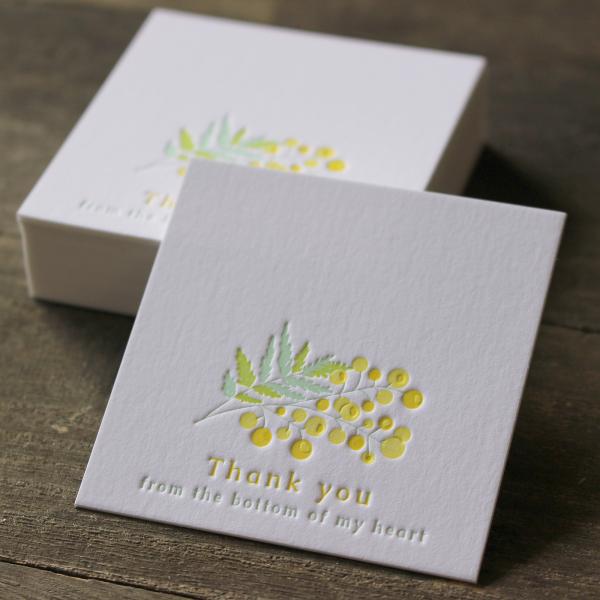 ミモザのイラストが入ったサンキューカード兼アクセサリー台紙です。紙はスノーブルという厚手の紙を使用しており、その名の通り雪のような白さと優しい手触りが特徴です。印刷には3色の活版印刷が用いられており、真っ白なスノーブルに明るく彩られたカラー...