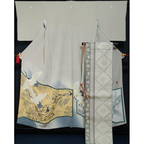 上質な白鼠色の浜ちりめん地に屏風に飛鶴模様が染められた色留袖と、薄グレー系の地に間道に菱華文、唐草模様が織られた袋帯、若緑色×金色の平組帯〆の３点セットです。柄付けは色留袖ですが、比翼は付いていません。本加賀友禅　向秀三氏のお着物で下前に落...