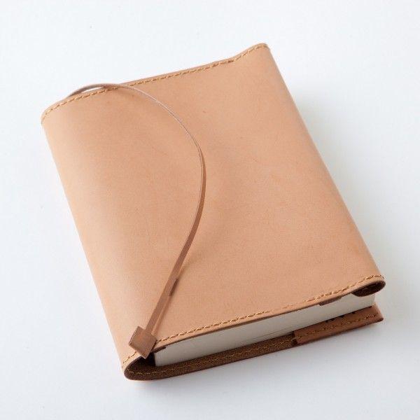 ヌメ革一枚革で仕上げたブックカバーです。本や日記を持ち歩いている方必見のブックカバーです。メイン材料のヌメ革は使用すればするほど、革特有の経年変化を楽しめます。丈夫な革を使用しているので、耐久性も抜群です。サイズは通常の小説サイズ（文庫A6...