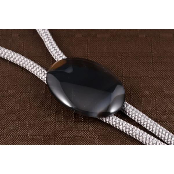 天然石を使用したループタイです。石には、特徴的な模様を持つブラックモンタナアゲートを使用しています。表面は滑らかに磨かれたカボションタイプで、乳白色の地色に灰色・黒・茶色の模様が入っています。落ち着いた印象のあるループタイです。石は半透明の...