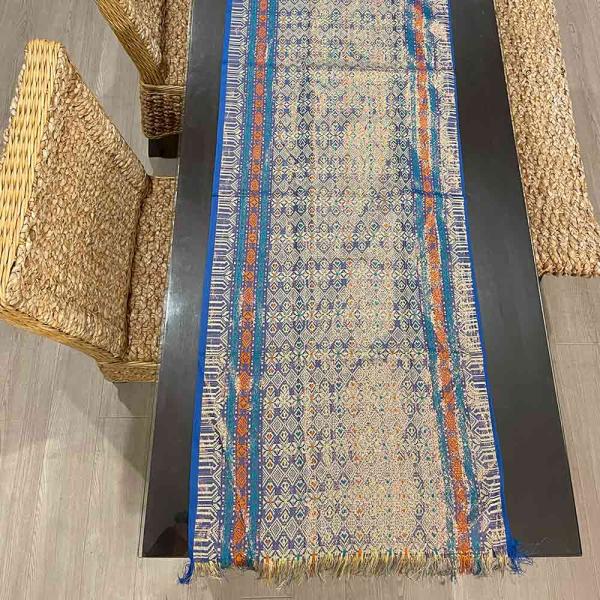 バリ島製　テーブルランナー、タペストリーなど、多用途にどうぞアジアンテイストな空間を演出するファブリックとして欠かせないアイテムであるイカットは縦糸と横糸から編まれる布です。明るい色合いで金糸使用のキラキラと光る華やかなタイプをセレクト。ダ...