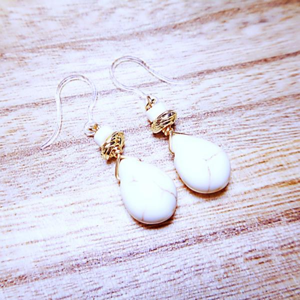 商品の大きさは定規と一緒に撮影されている写真をご覧ください。天然石ホワイトターコイズの樹脂ノンホールピアスです。ゴールドのメタルパーツを加えエスニックな印象に仕上げました。◎銅線にポリウレタン加工を施した 変色しにくいアーティスティックワイ...
