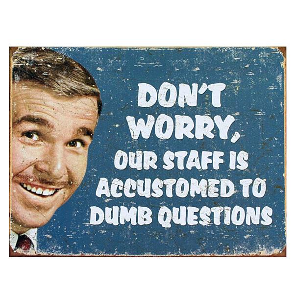 「DON'T WORRY, OUR STAFF IS ACCUSTOMED DUMB QUESTIONS」（心配しないで下さい！当社のスタッフはくだらない、馬鹿げた質問になれてますので！）と、描かれたユニークなティンサイン。笑顔でこちらを見...