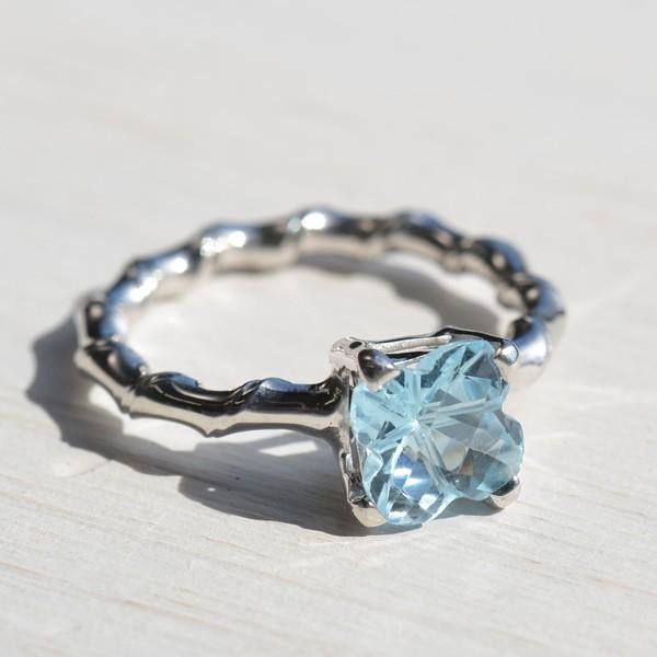 爽やかな明るい水色、透明感ばっちりのみずみずしいブルートパーズ。表はチェスカット状になっていて、複雑なきらめきが個性的なきらきらのフラワーカット。ねじりを加えたエタニティデザインです。素材：ブルートパーズサイズ：トップ約7×7mm、アーム幅...