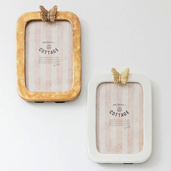 サイズ/約幅12×高さ17cm窓サイズ：約幅9×高さ13.5 cm対応写真サイズ：ポストカード、KG判内容量/1個材質/レジン、ガラス種類/ゴールド、ホワイト生産国/中国製●トップに小さな蝶をあしらったフォトフレームです。●上品なアンティー...