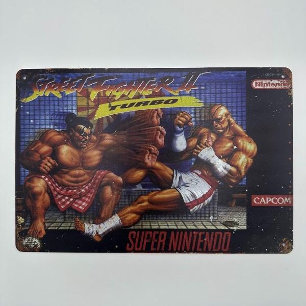 スーパーファミコンの名作格闘ゲーム『Street Fighter II TURBO』の名場面がデザインされたブリキ看板です。本商品は人気キャラクター「エドモンド本田」と「サガット」の熱い対決シーンを描いた一枚。横30cm、縦20cmのサイズ...