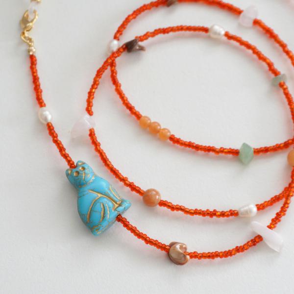 オレンジ色のビーズにターコイズカラーの猫や天然石・シェルが飾られた可愛いメガネチェーンです。シリコンパーツを外すとネックレスやマスクコードしてもお使い頂けます。【サイズ】全長約 76cm【素材】ビーズ、天然石、真鍮【ご注意事項】■ 天然素材...