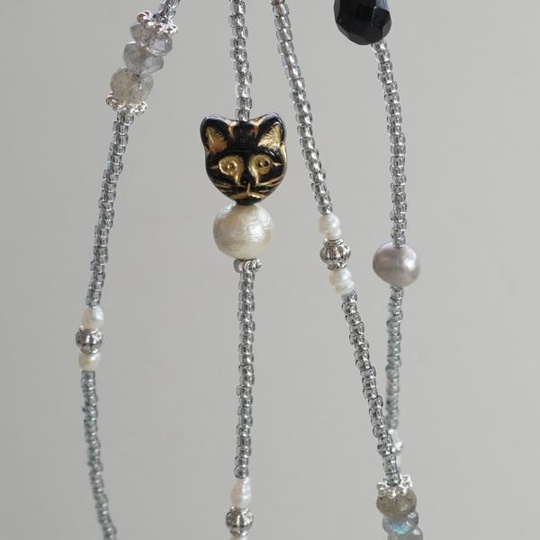 シルバー系のシードビーズに天然石のラブラドライト、シルバーパール、ブラックビーズをメインに飾られたメガネチェーンです。サイドに可愛いネコのモチーフが飾られています。シリコンパーツを外すとネックレスやマスクコードしてもお使い頂けます。【素材】...