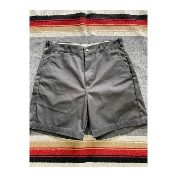 ポリエステル65%、コットン35%の混率で織り上げた頑丈なツイル生地を使用したワークショーツ。生地は肌触りの良さに加えシワになりにくく、特有の光沢感が特徴。TUF-NUTのヴィンテージトラウザースは尿素ボタン仕様のものが多くみられるが、利便...