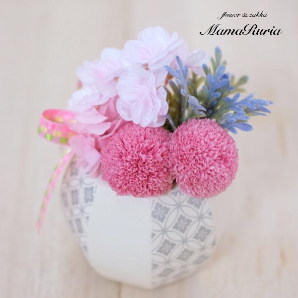ピンクのマムと、桜のアーティフィシャルフラワーのかわいいアレンジです。和風の器で、かわいらしさだけでなく、落ち着いたイメージもプラス！！母の日の贈り物や、お誕生日のお祝いなど、用途は様々。ラッピングしてお届けします。数量限定、プチプライスで...