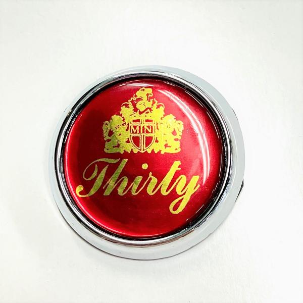 クラシックミニの丸型タイプのボンネット中央のエンブレムです。 生誕30周年記念のデザイン。センターのモチーフは樹脂コーティングされたステッカーです。 光により、濃い赤やピンクっぽくも見えるカラーリングです。貼り付けは両面テープで貼り付けるだ...