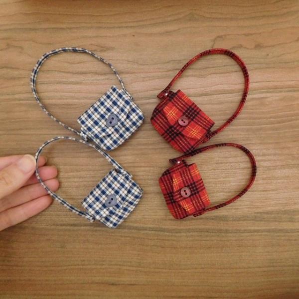 人形用の小さなショルダーバッグです。ブルー系と赤系チェックの、ミニショルダーバッグです。小脇に抱えるように肩に掛けるデザインの、ストラップ短めのショルダーバッグです。フラップには、飾りボタンが付いています。ストラップは、片側がスナップで取り...