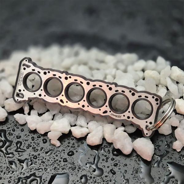 日産RB20エンジン用シリンダーヘッドガスケットを精密に再現したミニチュアキーチェーン。厚さ2mmのステンレスに職人の手でブラッシュ仕上げを施した、ドイツ製のこだわりの逸品。コンパクトながら、細部まで丁寧に再現されており、大量生産では決して...