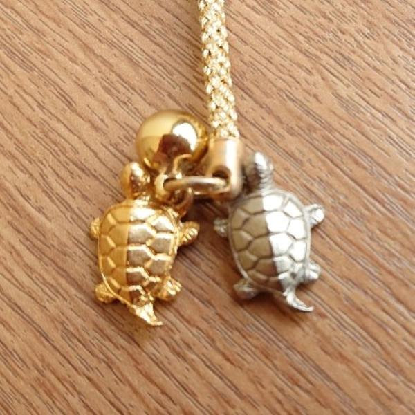 金銀の亀の根付(ストラップ)です。亀は長寿の象徴ですが、甲羅が小判等のお金に似ていることから金運も招くとも言われております。・サイズ 亀本体:全長約20mm、甲羅の幅約8mm和小物・金銀・かめ・トータス・turtle・根付・ストラップ・招福...