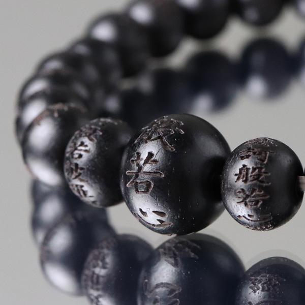 仏の教え、般若心経の真髄を彫刻した数珠ブレスレットでございます。素材は、艶消しの黒檀でございます。黒檀は使い込む程に天然木の風合いをお楽しみいただける、素引き黒壇を使用しております。親玉と天玉を除く一玉一玉にお経の一説が彫られており、ブレス...