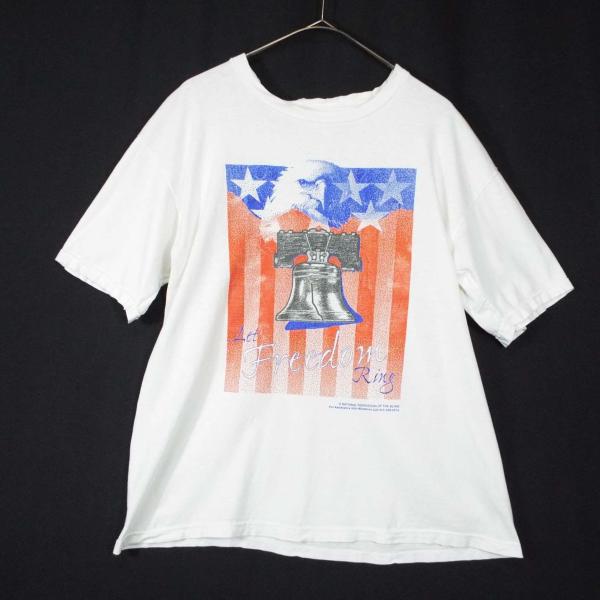 【当店スタッフのお薦めポイント】・星条旗とイーグルをモチーフにしたビッグプリントTシャツ・襟の伸び感も◎【商品詳細】・ブランド：不明（タグなし）・スタイル：丸首 半袖Tシャツ・お色：ホワイト系・素材：コットンまたはコットン混・表記（USサイ...