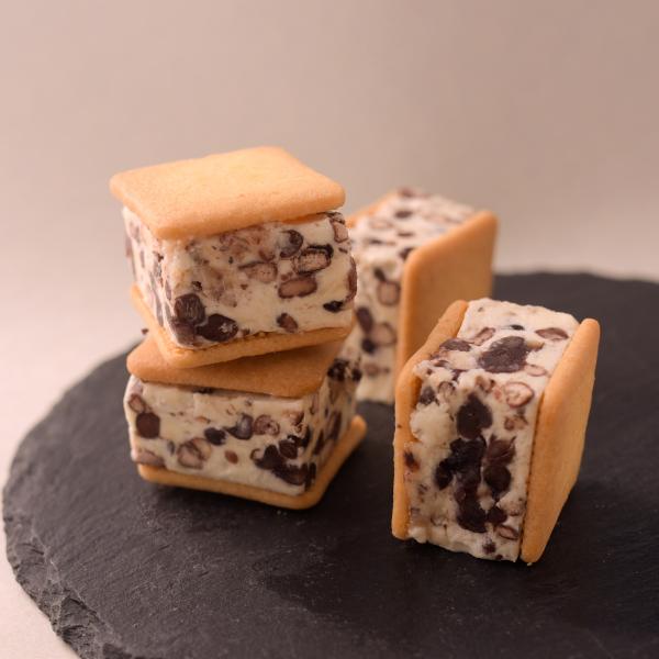 カリカリ食感のフリーズドライの小豆とホクホク食感の甘納豆小豆の2種を、塩味を効かせたサッパリとした軽いバタークリームに混ぜ込んだ「TABLES 堀江バターサンド 塩あんバター」です。バタークリームのほのかな塩味とサクサクのサブレが相まって、...