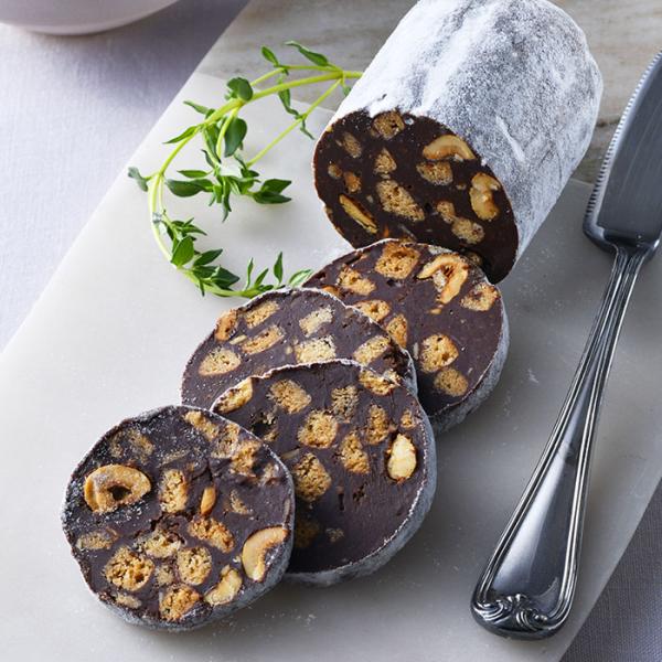 ナッツやビスケットをチョコレートに混ぜ込んで固め、粉糖をまぶして白カビサラミに見立てた遊び心ある一品。ショコラのなめらかな口溶けとともに、ザクザク＆カリッとした食感が弾け、濃厚なのにほろっと崩れる軽やかさが秀逸だ。好みの厚さにカットしてどうぞ。