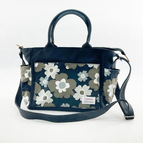 フロントの花柄ポケットが目を引く、かわいらしく上品なデザインが魅力です。取り外し可能なショルダーストラップ付きで、ハンドバッグとショルダーバッグの2通りでお使いいただけます。縦22cm×横26cm×マチ12cmのコンパクトながら使いやすいサ...