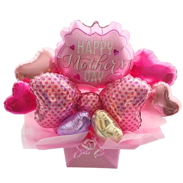 母の日のプレゼントにぴったりな、ピンクカラーが華やかなバルーンアレンジメントです。 中央には「Happy Mother's Day」と書かれた大きなフォイルバルーンが飾られ、周囲にはハート型やドット柄のかわいいバルーンが彩り豊かに配置されて...