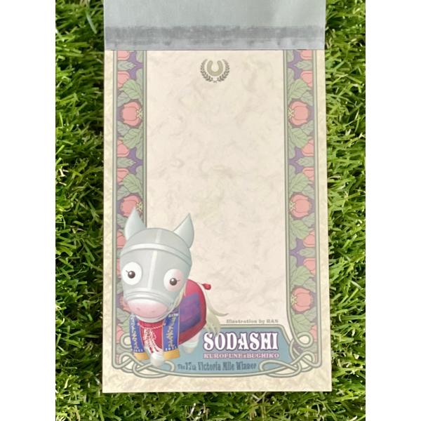 【発売日：2022年06月25日】ヴィクトリアマイルの優勝レイと馬着を着けたソダシのイラストのクロス巻きメモ帳です。縦12cm×横8cmで40枚綴り、表紙に無地のトレーシングペーパーが付いていて上部を黒のクロスで綴じる形になってます。1枚ず...