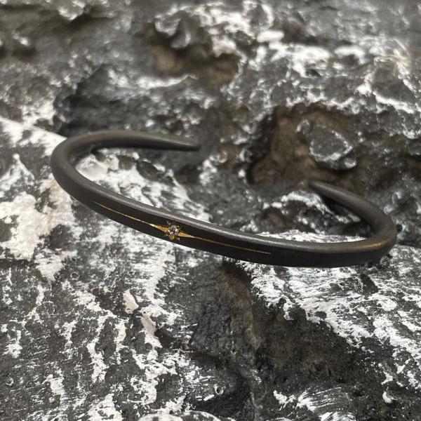 全て手作業で作られるダイアモンドを彫り止めした黒く燻された真鍮製バングル。※化学反応により黒く燻しておりますので摩擦や汗、引っ掻き等で変色を起こすことがございますが経年変化としてお楽しみください。素材 : Brass Diamondサイズ : M