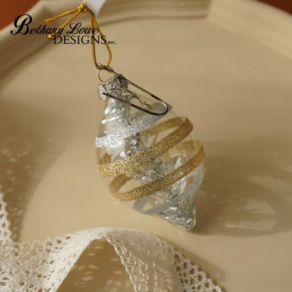 透明なガラスボールにシルバーとゴールドのストライプが描かれた、おしゃれなオーナメントです。クリアボールとキラキラ輝くグリッターを組み合わせたオーナメントは、シンプルならがも存在感を感じられるデザインに仕上がっています。ボールの中のシルバーモ...