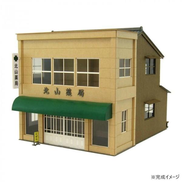 看板建築の薬屋さんのキットです。正面扉が4枚の引き戸で、その両側にも大きなガラス窓がはまっている、間口の広い看板建築です。ファサードのベージュ色と板貼りの茶色のバランスが素敵で落ち着いた雰囲気のある建物です。裏の物干し台にも注目です。シャー...