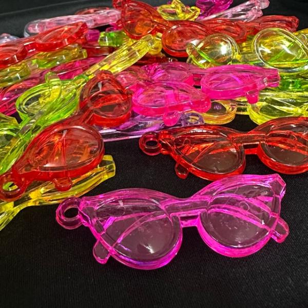 サングラスモチーフのアクリルチャームです。8個でのランダムカラー販売です。ランダムの為、色指定や色個数は選べません。　全て違う色では無く、同色が2個入る場合もございます。サイズ　約63.5mmx20mmx8mm 穴：4mm素材　アクリル小傷...