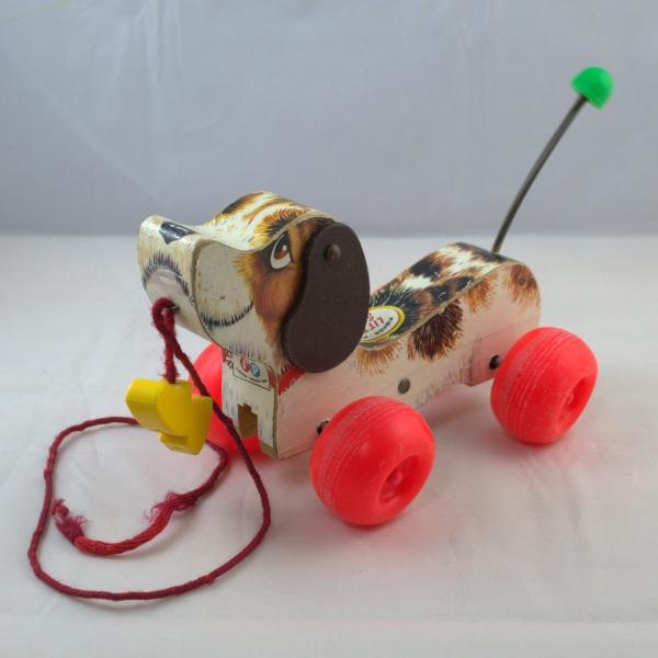 フィッシャープライス　LITTLE　SNOOPY。スヌーピープルトイ、Fisher Price　Toys 1960年代アメリカ製 です。口に黄色い靴をくわえていて、紐を引っ張ると曲がった車輪が回転してカタカタを音が鳴って尻尾を振りながら動き...