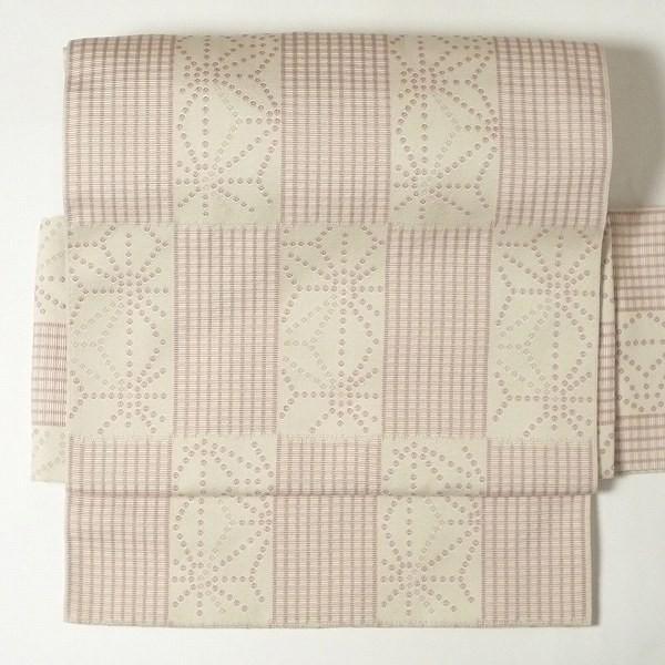 白地にピンク色の糸で市松模様を織り出しました。市松部分は麻の葉文と格子になっています。クラシックな柄ですが、モダンな印象のおしゃれな名古屋帯です。