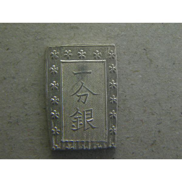 品位　銀８７３／その他１２７　量目８．６３ｇ　天保一分銀と比べますと、切り方が荒く、それが安政一分銀の特徴にもなっています。また、「是」字の第８画と９画が交叉しておらず、人になっています。側面の仕上げは、概して荒いやすり目が入っています。（...