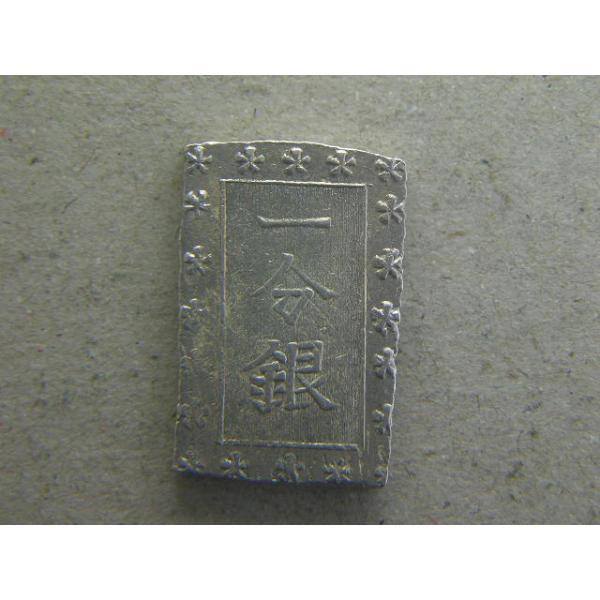 品位　銀８７３／その他１２７　量目８．６３ｇ　天保一分銀と比べますと、切り方が荒く、それが安政一分銀の特徴にもなっています。また、「是」字の第８画と９画が交叉しておらず、人になっています。側面の仕上げは、概して荒いやすり目が入っています。（...